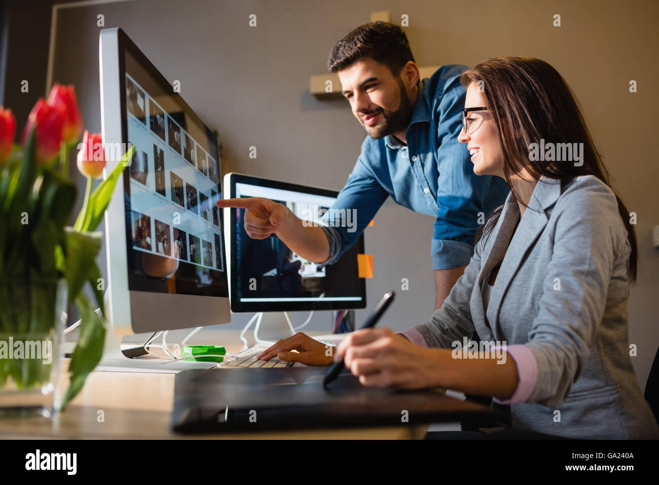 Graphic designer pointing at monitor Stock Photo - Alamy