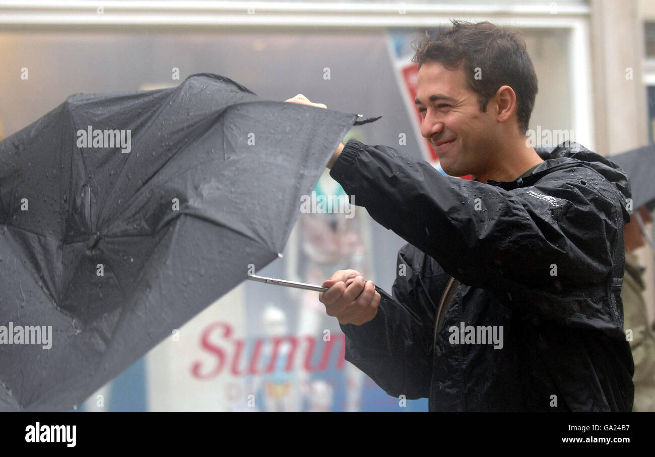 A man fights with his umbrella during heavy rain and wind in York today ...