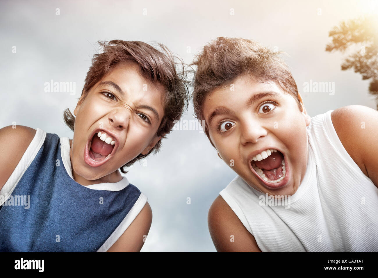 Portrait of a two crazy boys screaming to camera, over gray sky ...