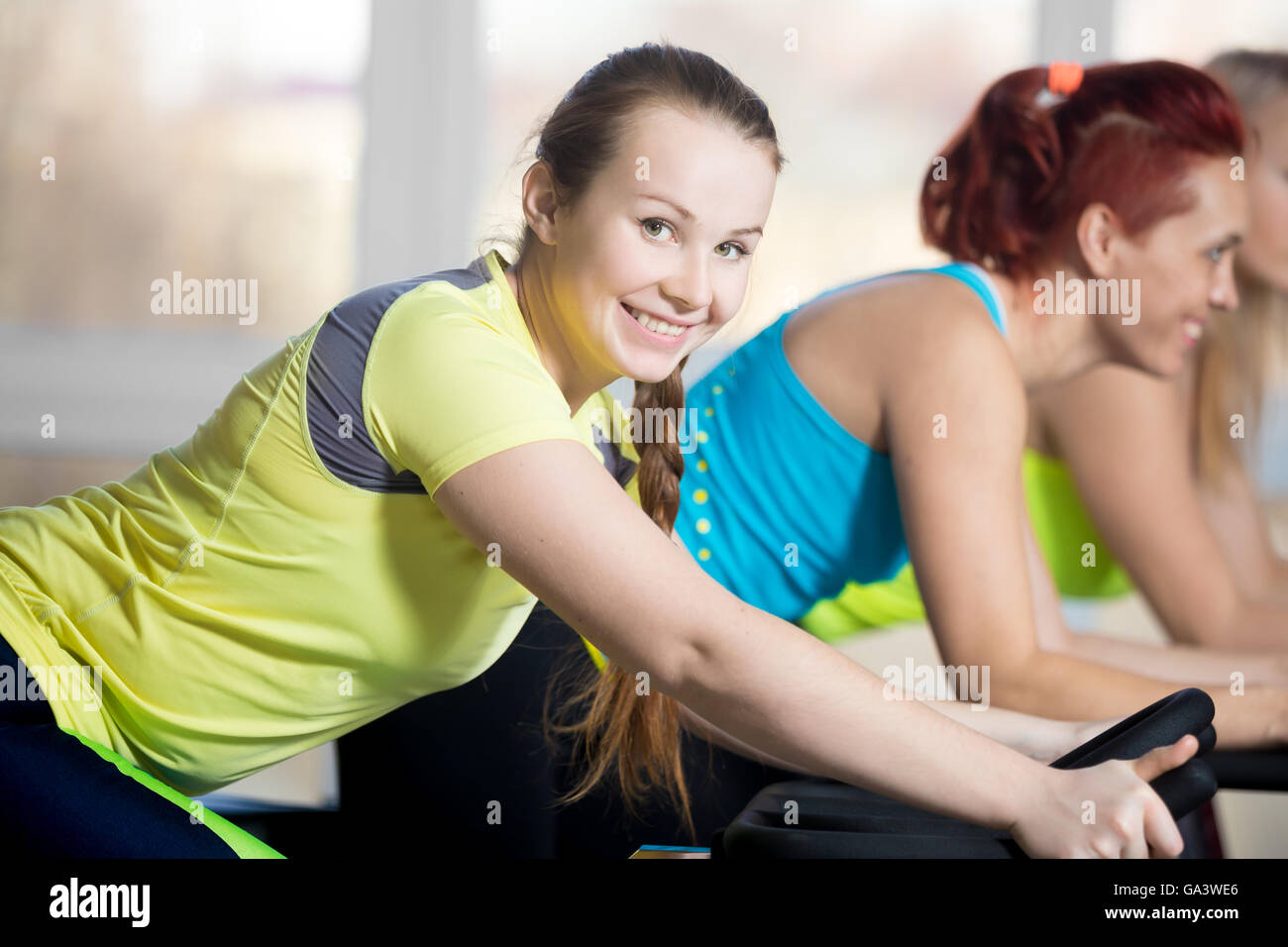 Fitness practice, group of beautiful cheerful females cycling in sports ...
