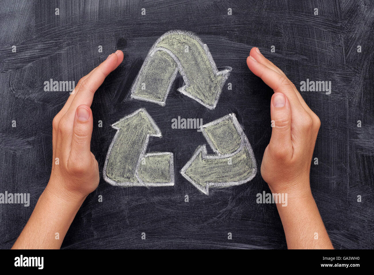 Hands protecting Recycle sign on black chalkboard background. Close up ...