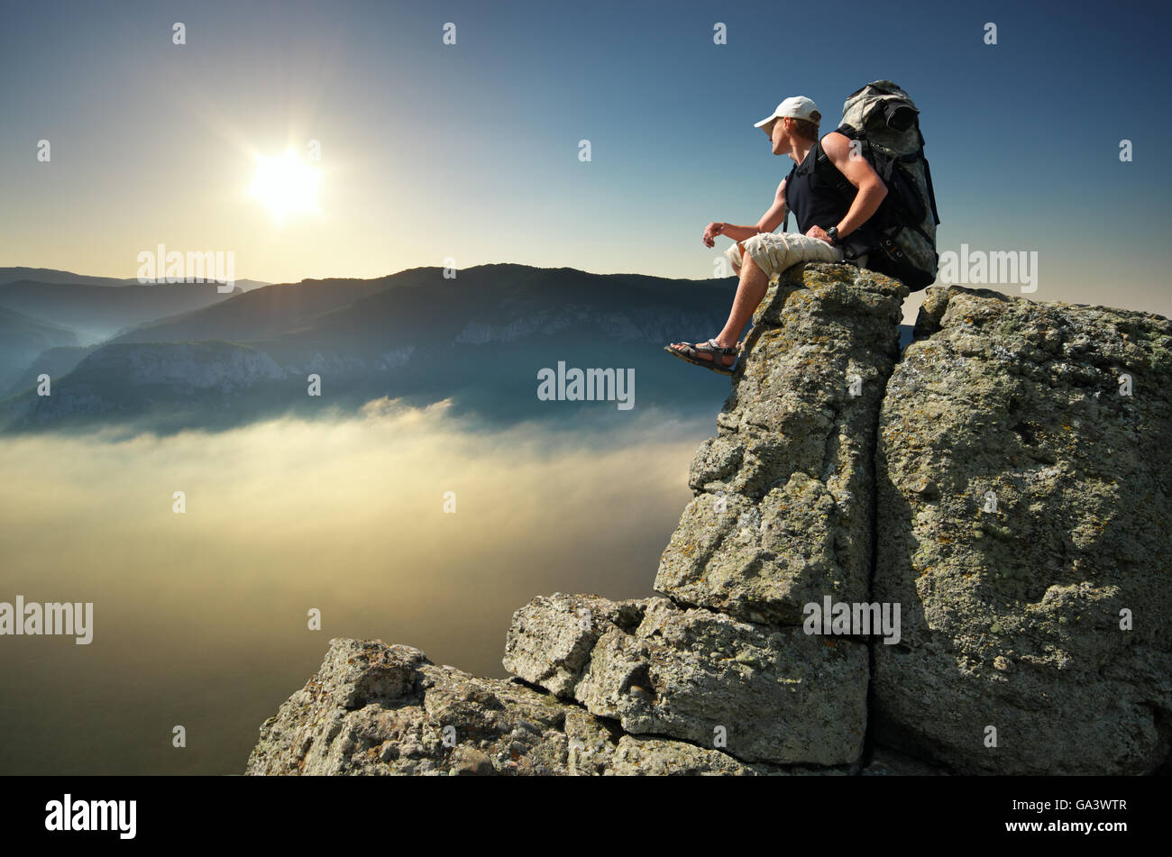 Man in mountain sitting on the cliff. Conceptual scene Stock Photo - Alamy