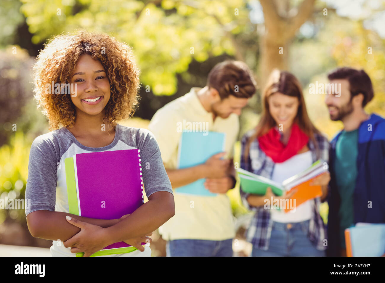 Portrait of college girl holding notes with friends in background Stock ...