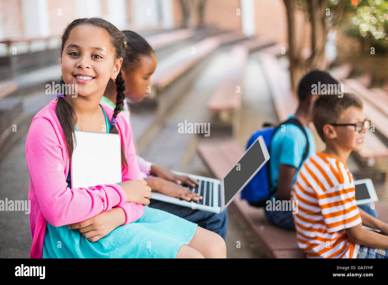Kids sitting on bench and using laptop Stock Photo - Alamy