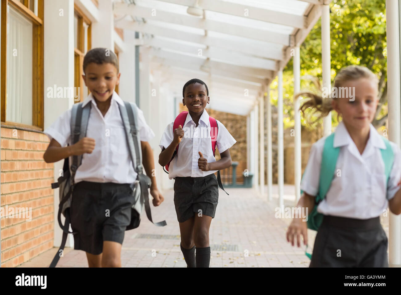 Smiling school kids running in corridor Stock Photo - Alamy