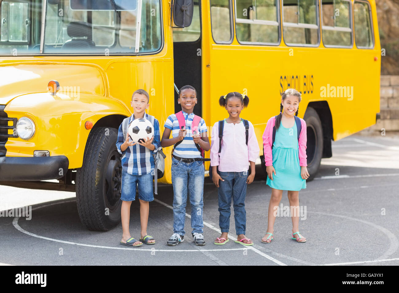 Smiling kids standing together in front of school bus Stock Photo - Alamy