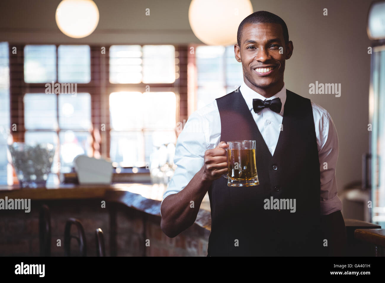 Smiling bartender offering a glass of beer at bar counter Stock Photo ...