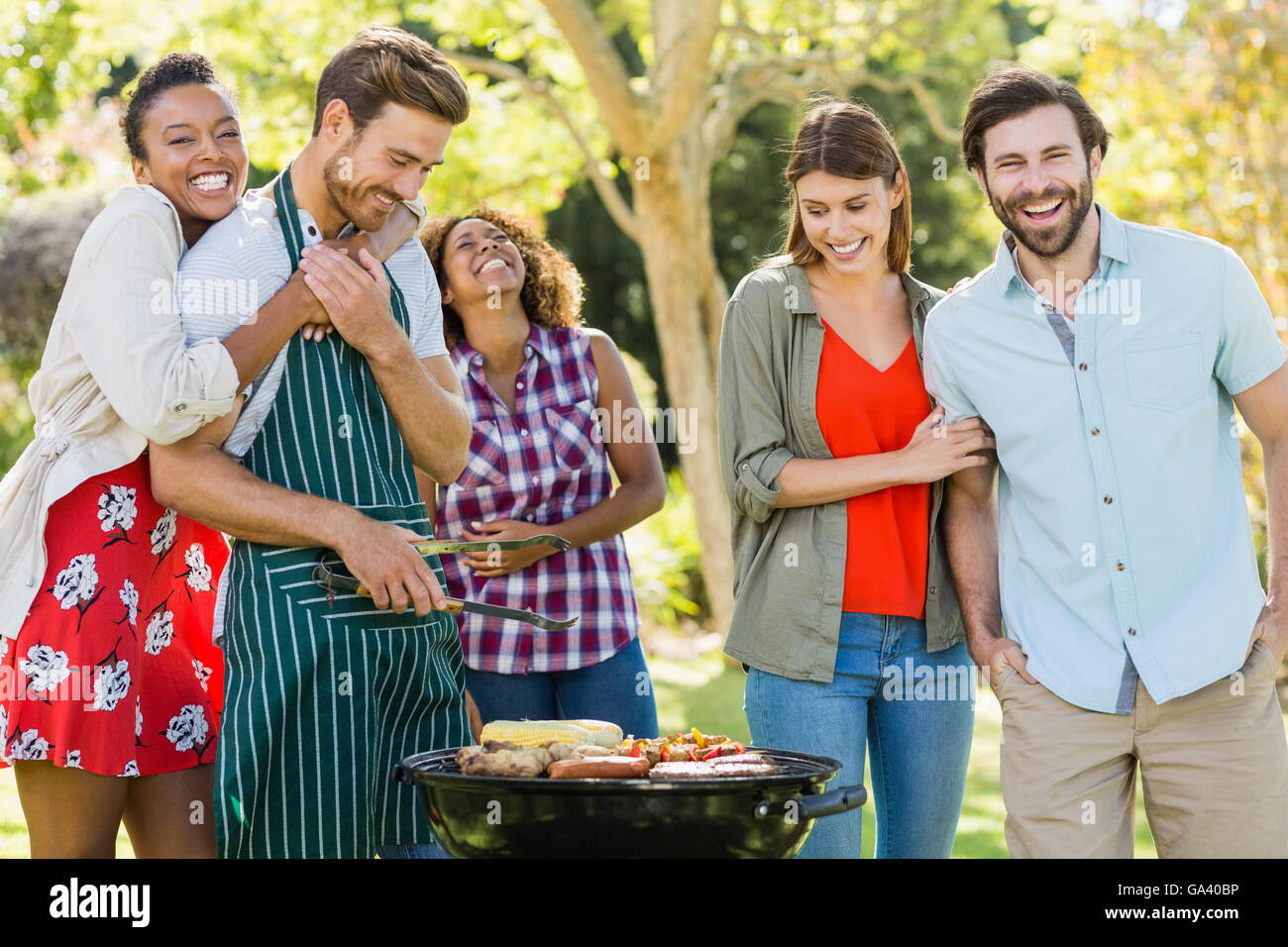 Happy friends preparing a barbecue grill in park Stock Photo - Alamy