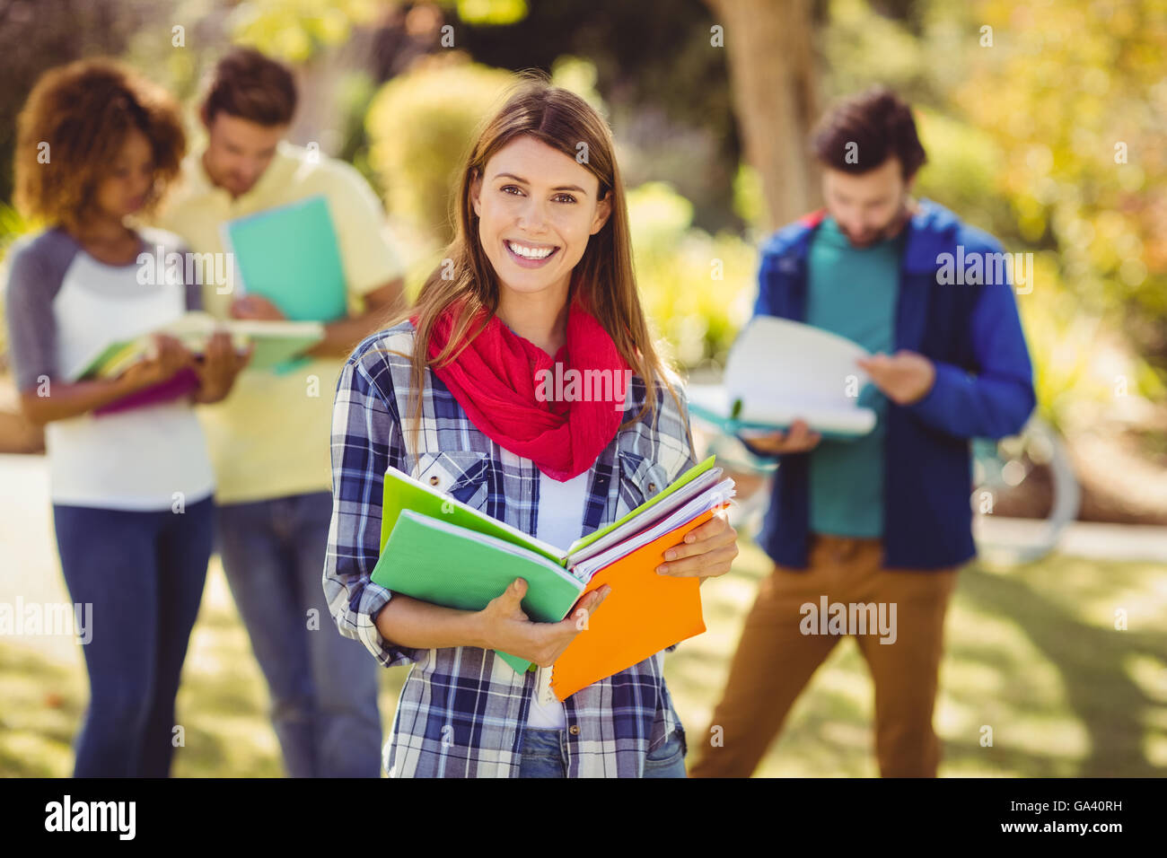 Portrait of college girl holding notes with friends in background Stock ...