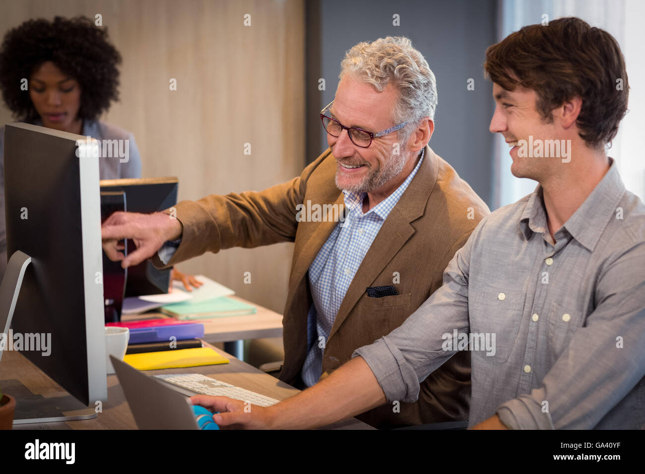 Businessman explaining colleagues over computer Stock Photo - Alamy