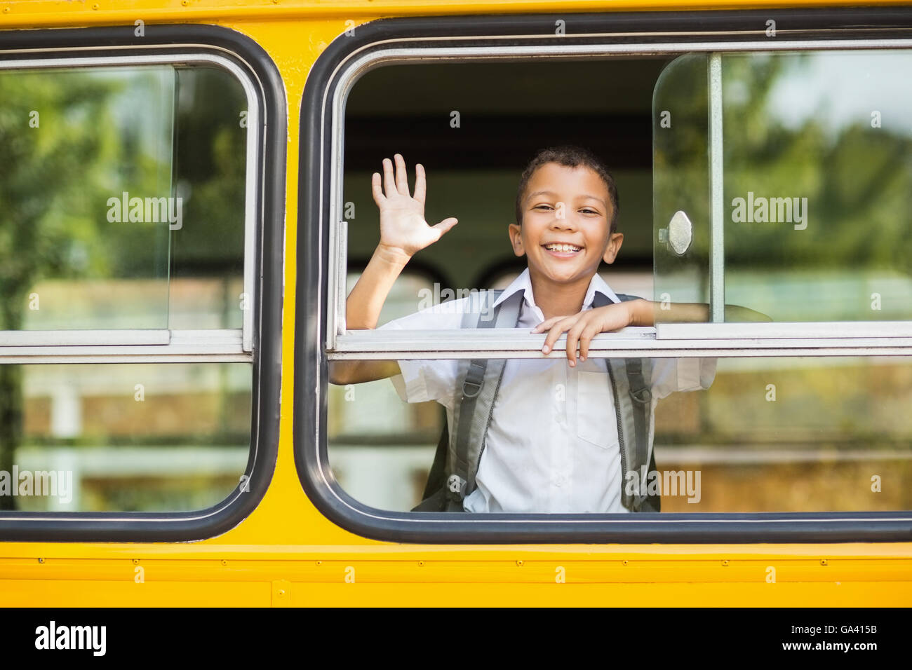 Smiling schoolboy waving hand from bus Stock Photo - Alamy