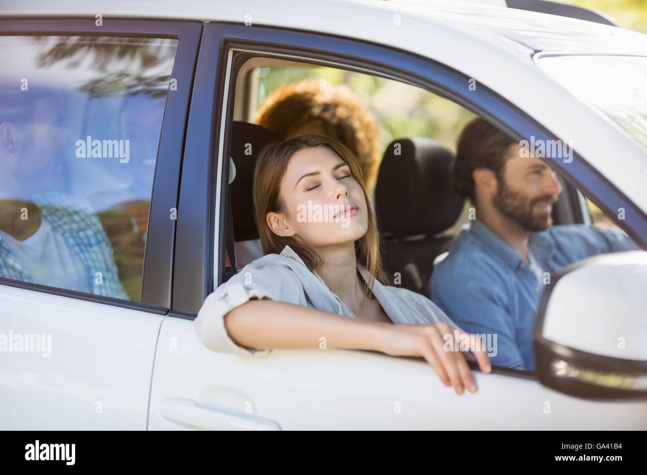 Beautiful woman relaxing in car with friends Stock Photo - Alamy