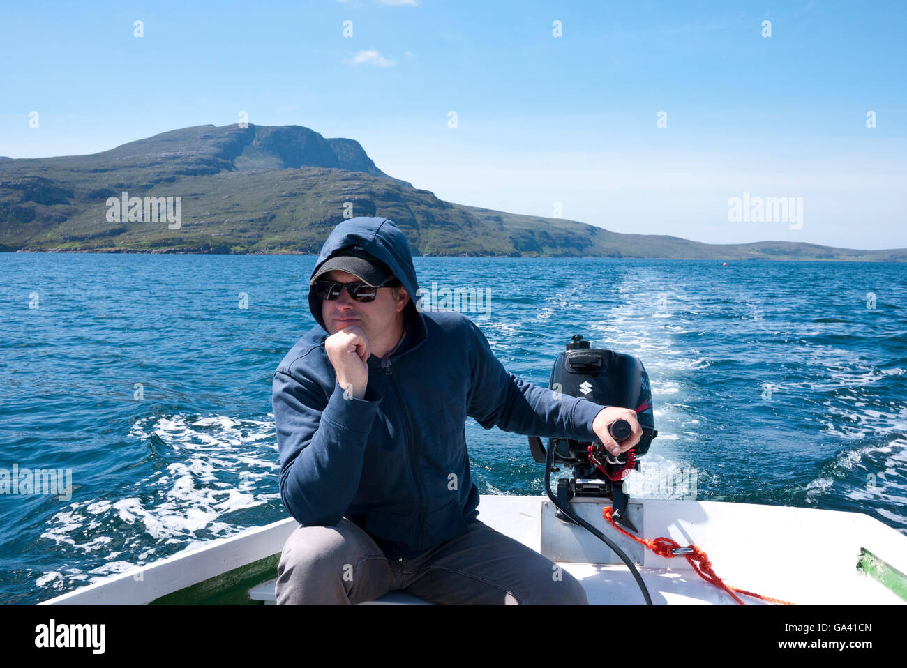 Young man in a boat using outboard motor, Scottish Highlands, UK Stock ...