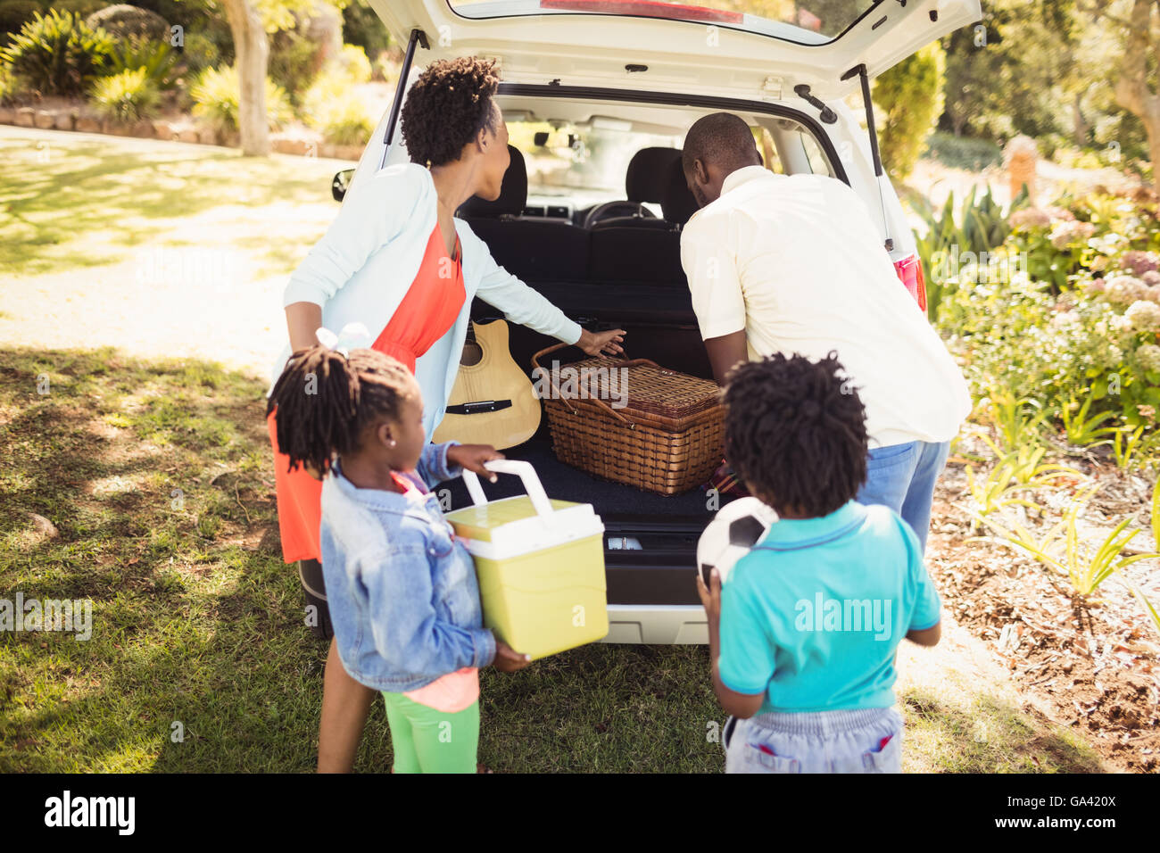 Happy family taking objects out of the car Stock Photo - Alamy