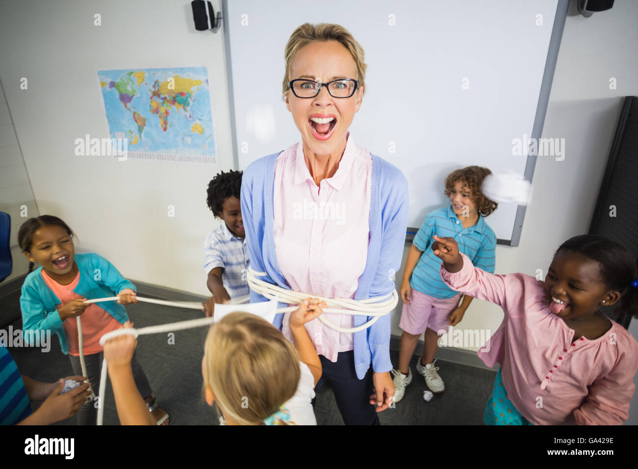 Students tying up a teacher with rope in classroom Stock Photo - Alamy