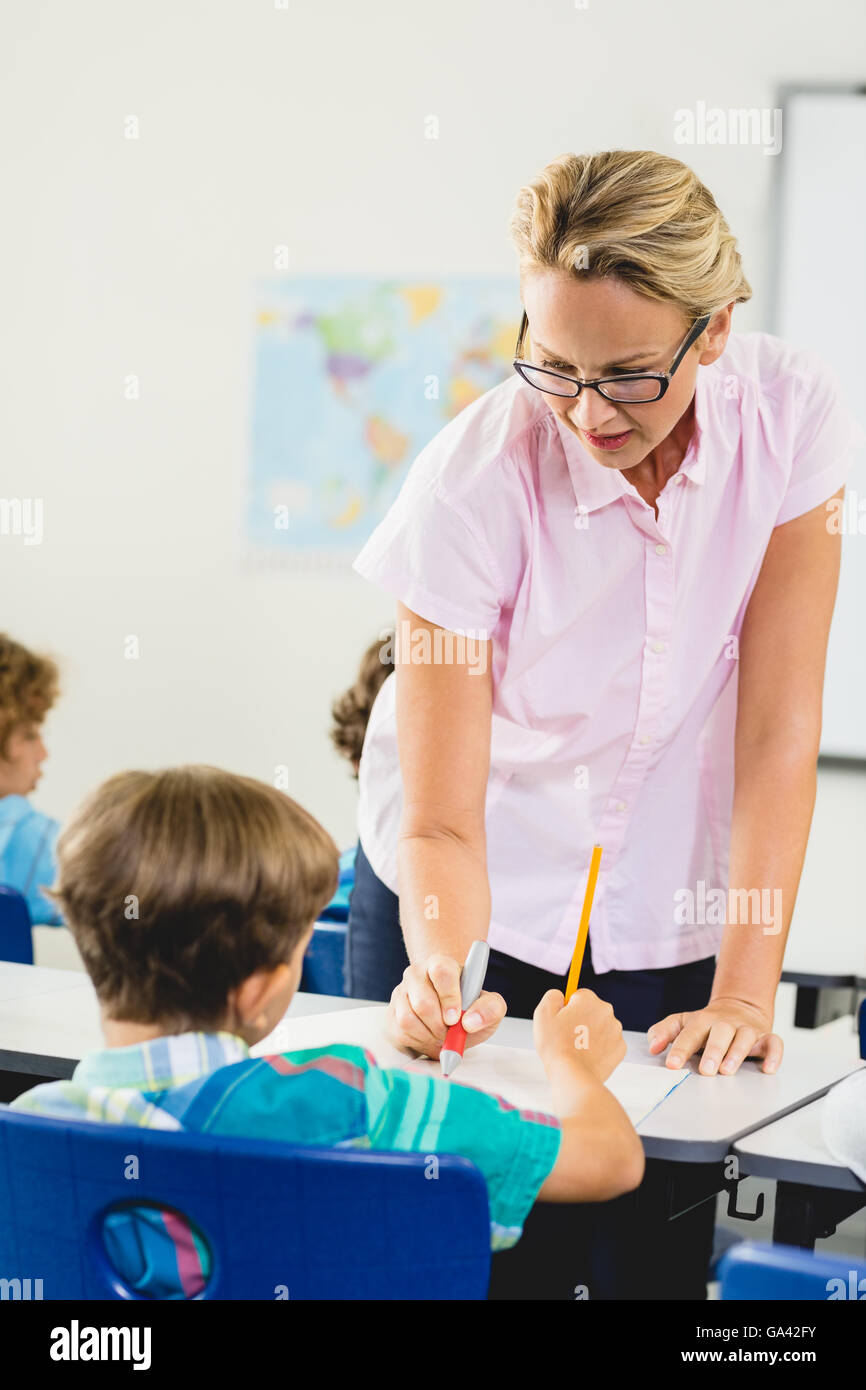 Teacher helping kids with their homework in classroom Stock Photo - Alamy