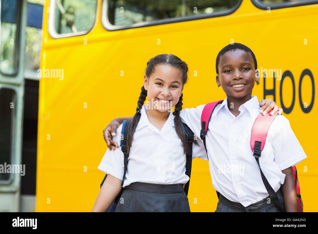 Smiling kids standing in front of school bus Stock Photo - Alamy