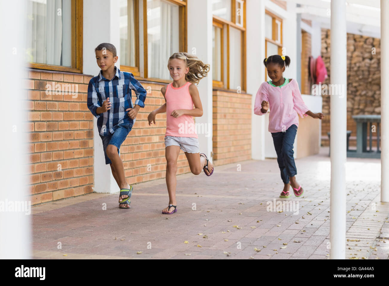 Smiling school kids running in corridor Stock Photo - Alamy