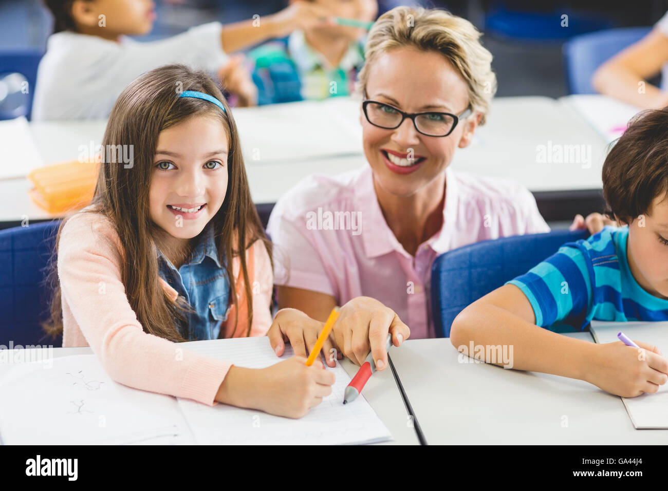 Teacher helping a girl with study's in classroom Stock Photo - Alamy