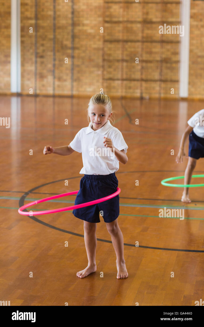 Schoolgirl playing with hula hoop in school gym Stock Photo - Alamy