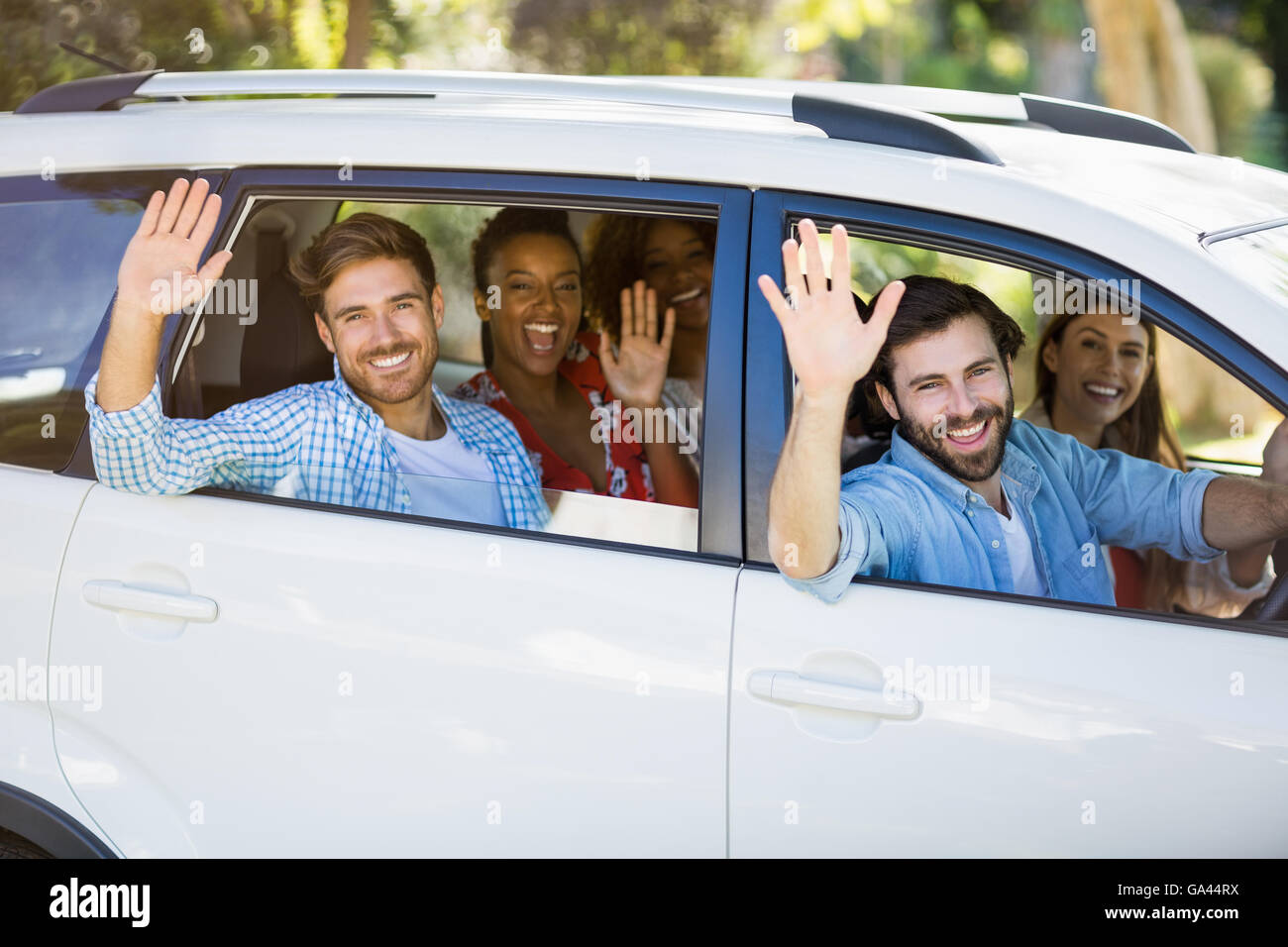 Group of friends waving hands from car Stock Photo - Alamy