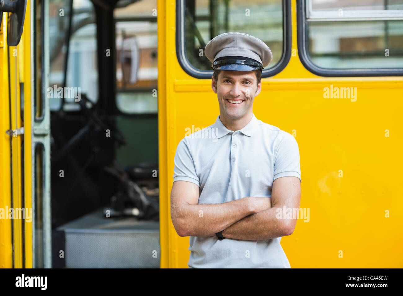 Smiling bus driver standing with arms crossed in front of bus Stock ...