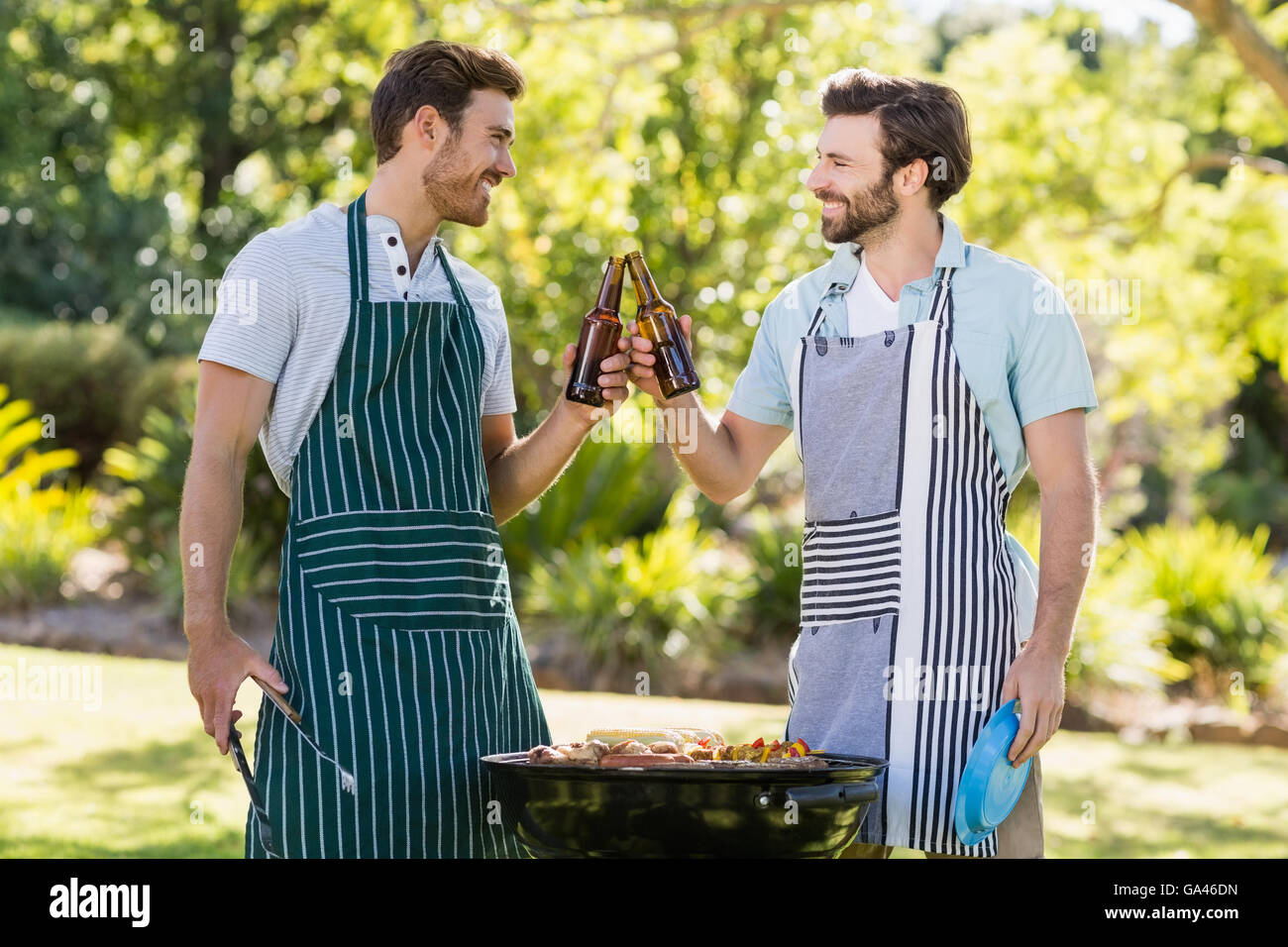Men toasting beer bottle while preparing barbecue grill Stock Photo - Alamy
