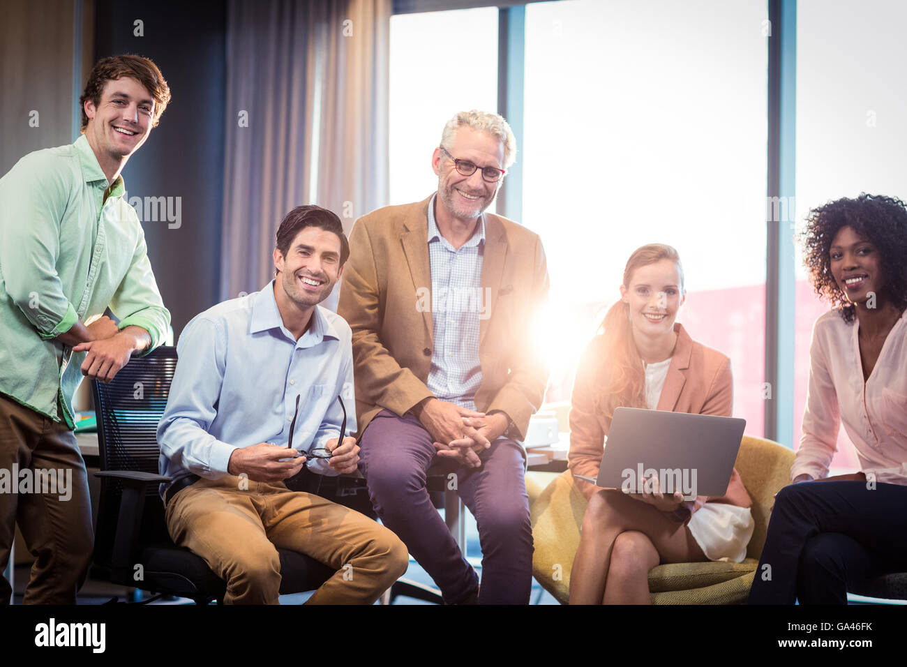 Portrait of business people smiling while having discussion over tablet ...