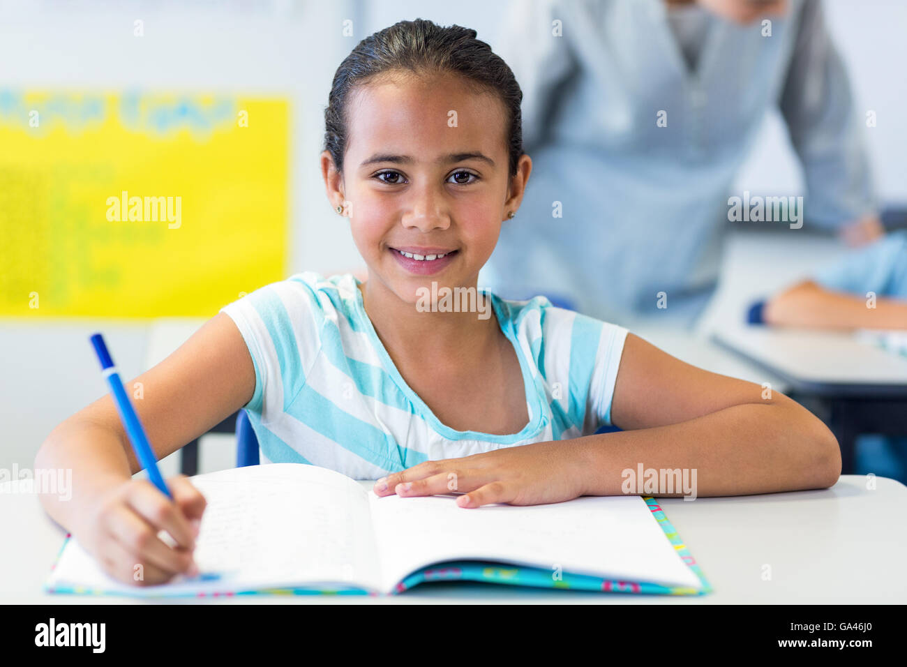 Portrait of smiling girl writing on book Stock Photo - Alamy