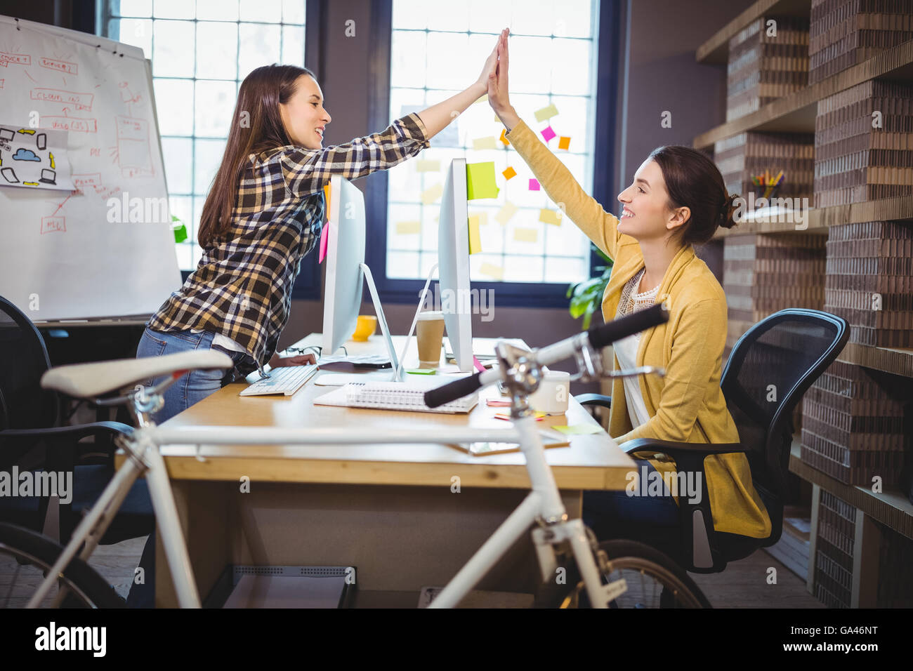 Female colleagues high fiving at computer desk Stock Photo - Alamy