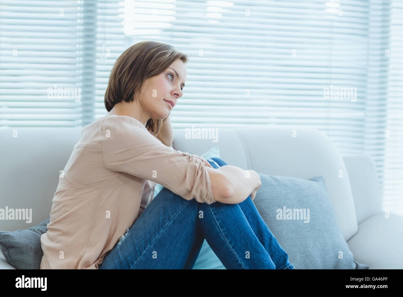 Sad woman sitting on sofa Stock Photo - Alamy