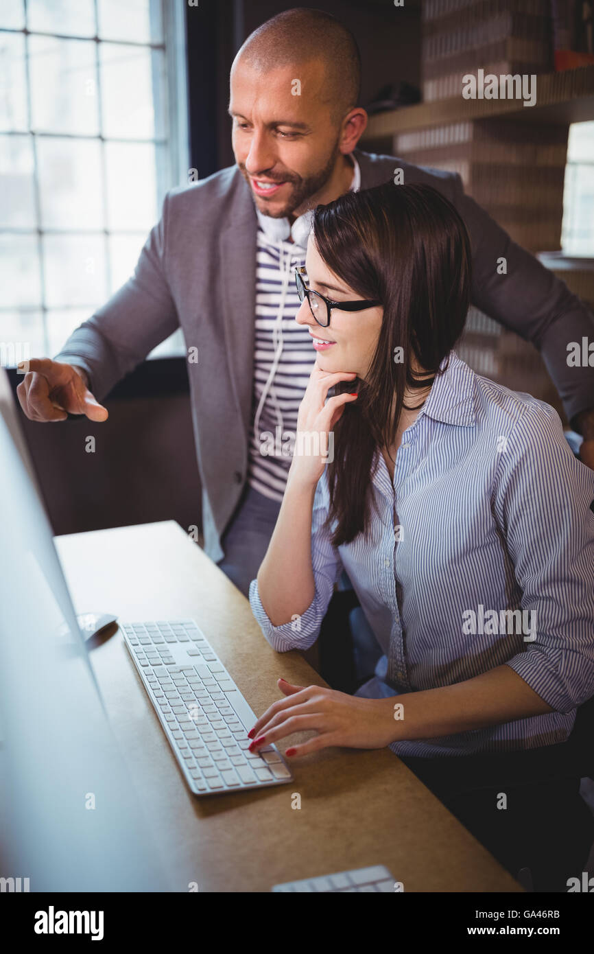 Businessman explaining female coworker over computer Stock Photo - Alamy