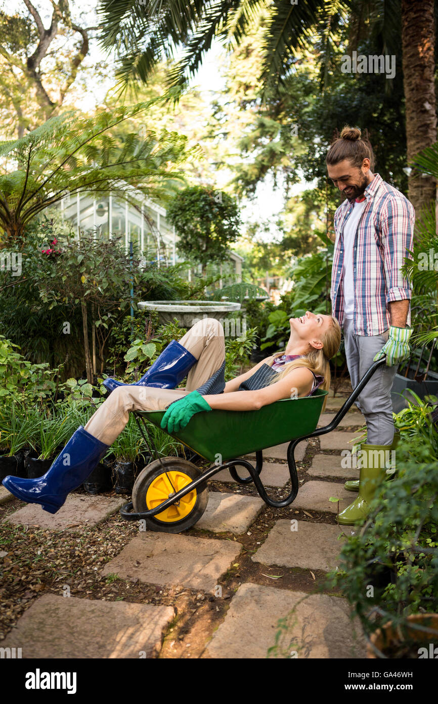 Happy colleagues enjoying with wheelbarrow in garden Stock Photo - Alamy