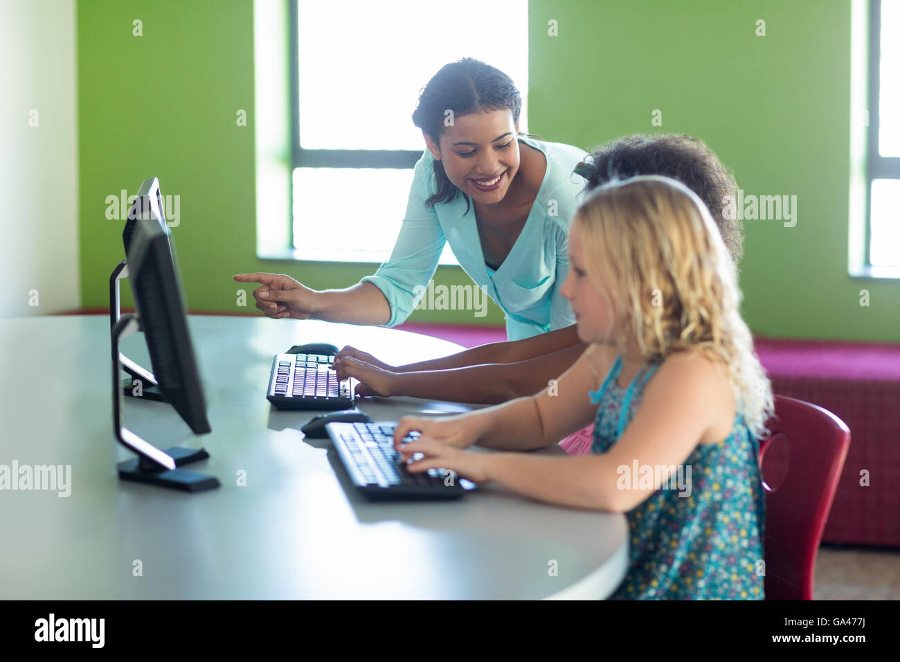 Female teacher teaching computer with children Stock Photo - Alamy