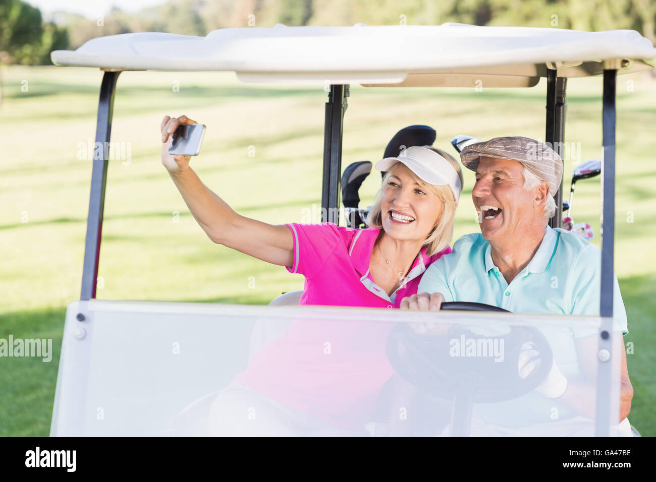 Couple taking selfie while sitting in golf buggy Stock Photo - Alamy