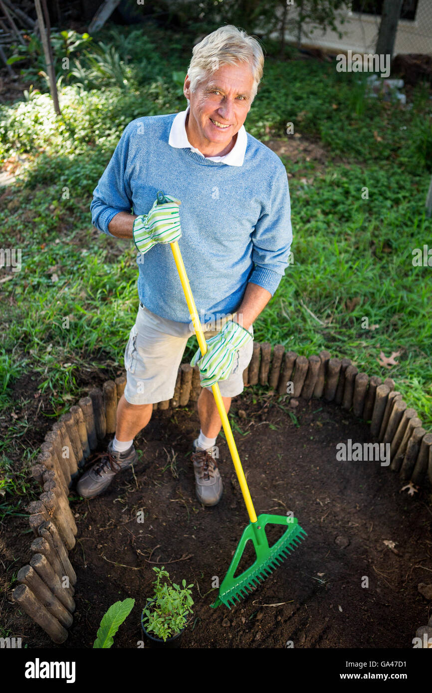 Portrait of happy gardener using rake at garden Stock Photo - Alamy