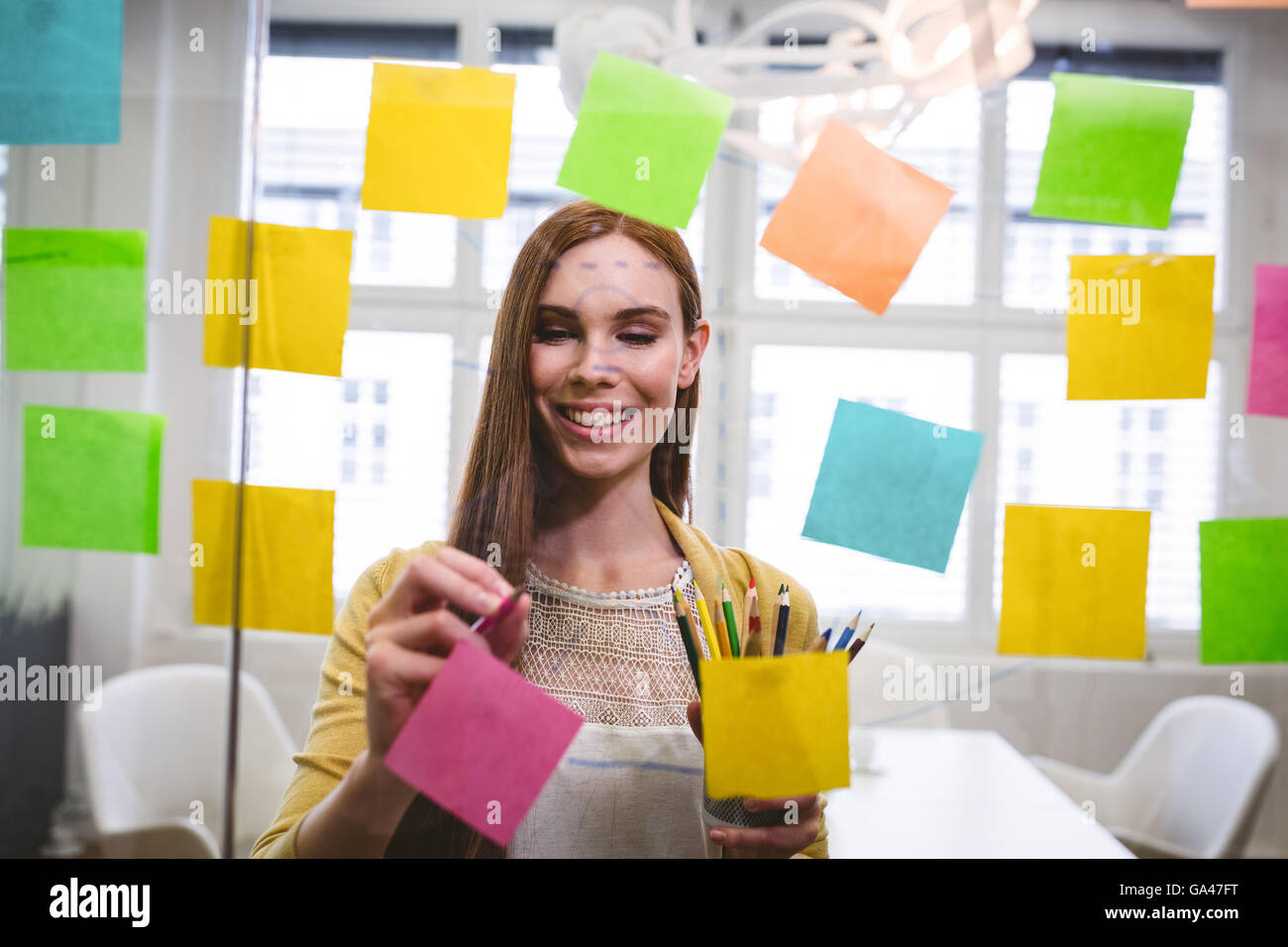 Businesswoman writing on sticky notes Stock Photo - Alamy
