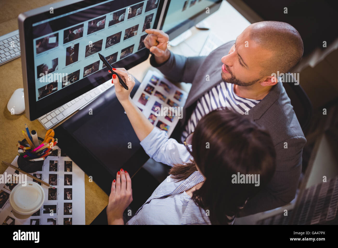 Coworkers discussing over computer at desk Stock Photo - Alamy