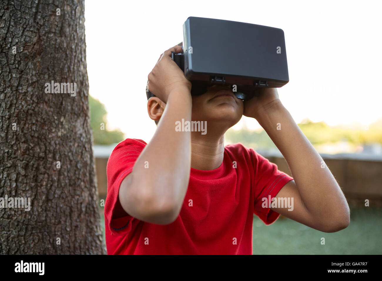 Elementary boy using virtual reality headset at park Stock Photo - Alamy