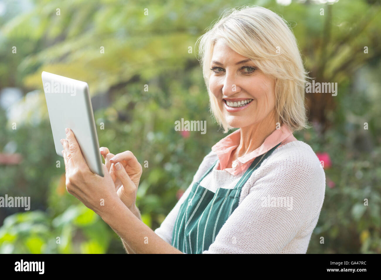 Happy mature female gardener using digital tablet Stock Photo - Alamy