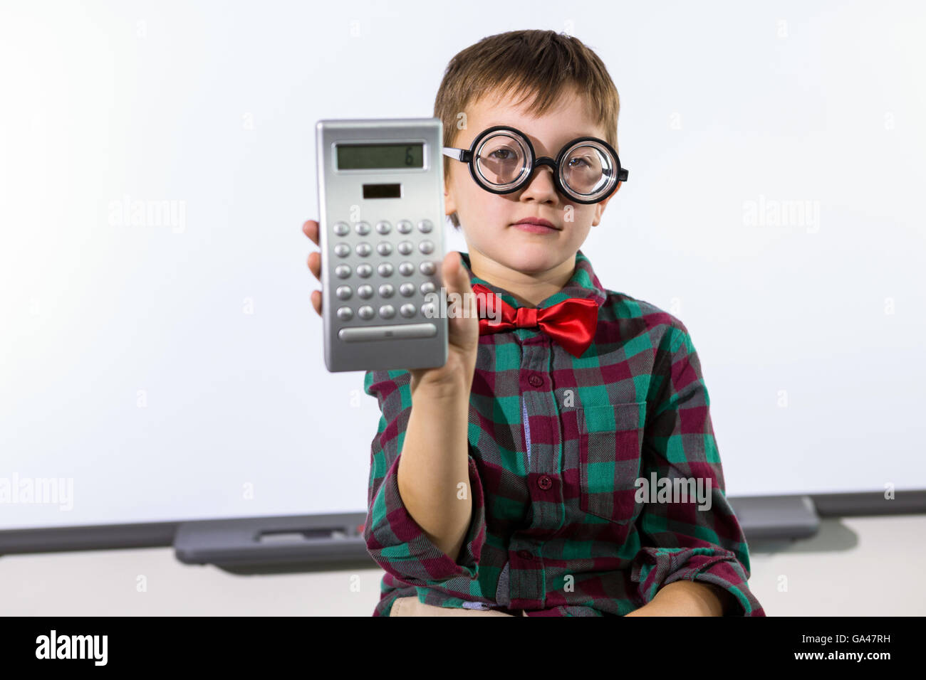 Portrait of elementary boy holding calculator in classroom Stock Photo ...