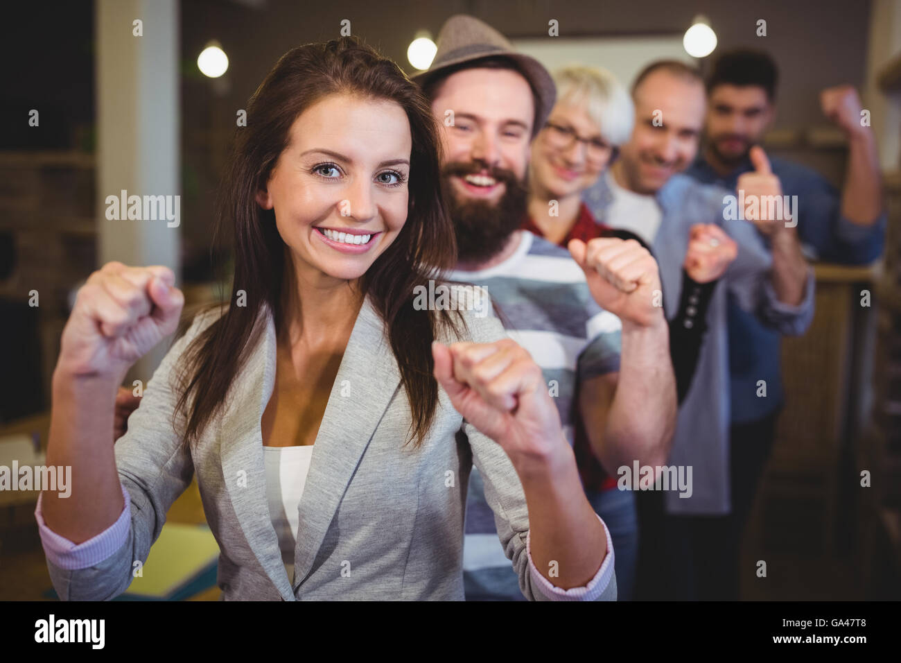 Coworkers cheering with clenched fist in creative office Stock Photo ...