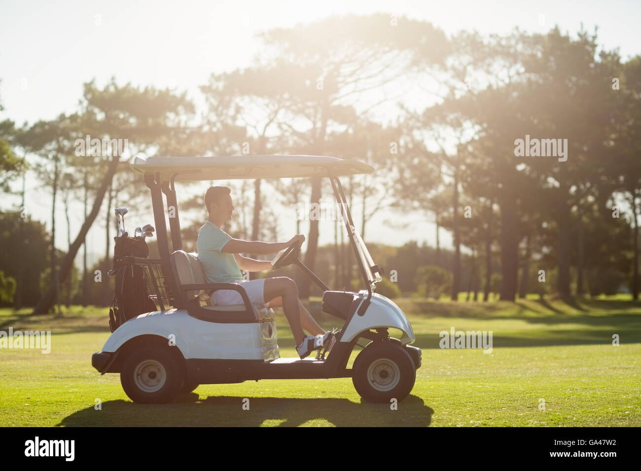 Side view of man sitting in golf buggy Stock Photo - Alamy