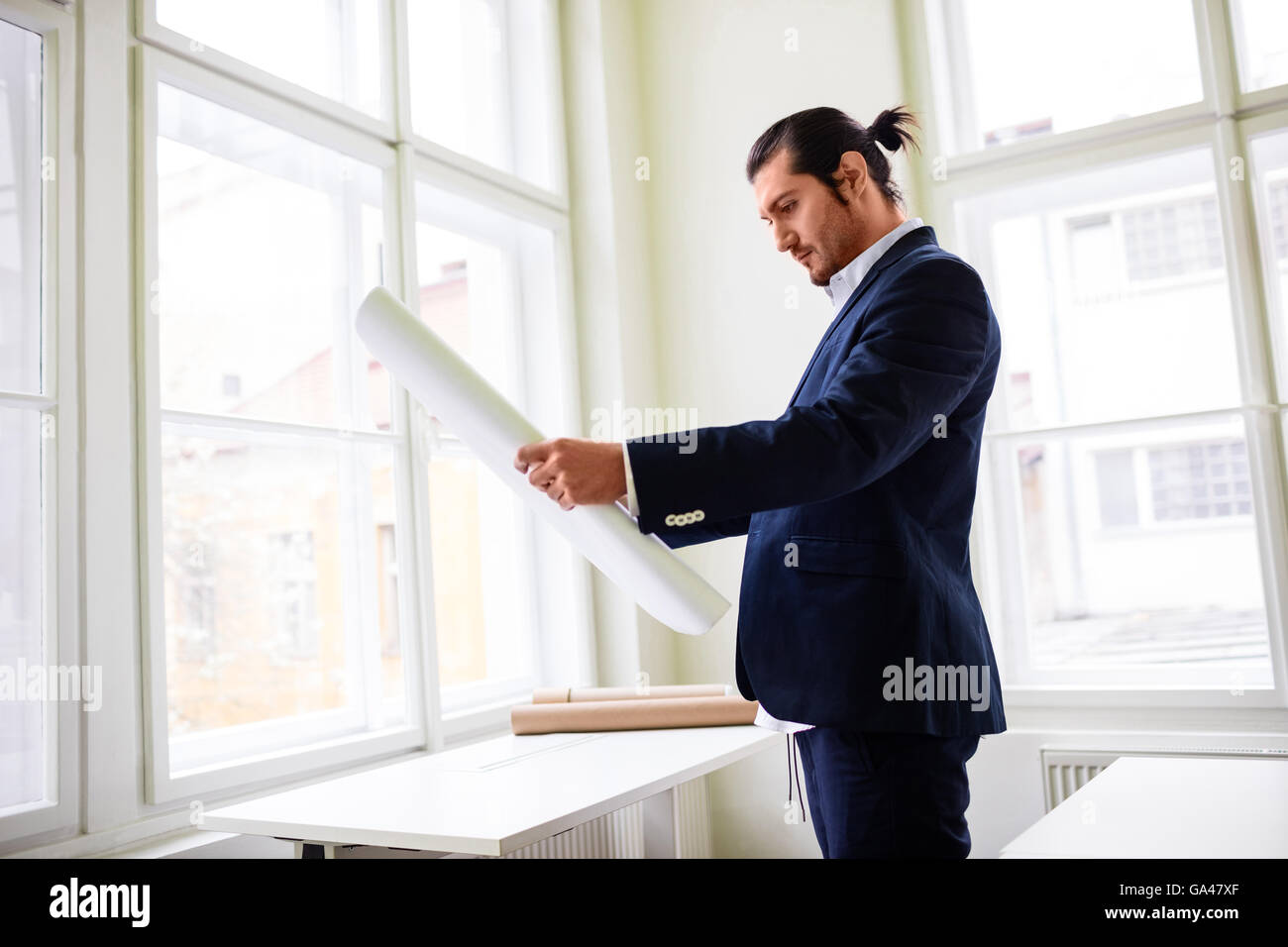 Confident architect holding blueprint Stock Photo - Alamy