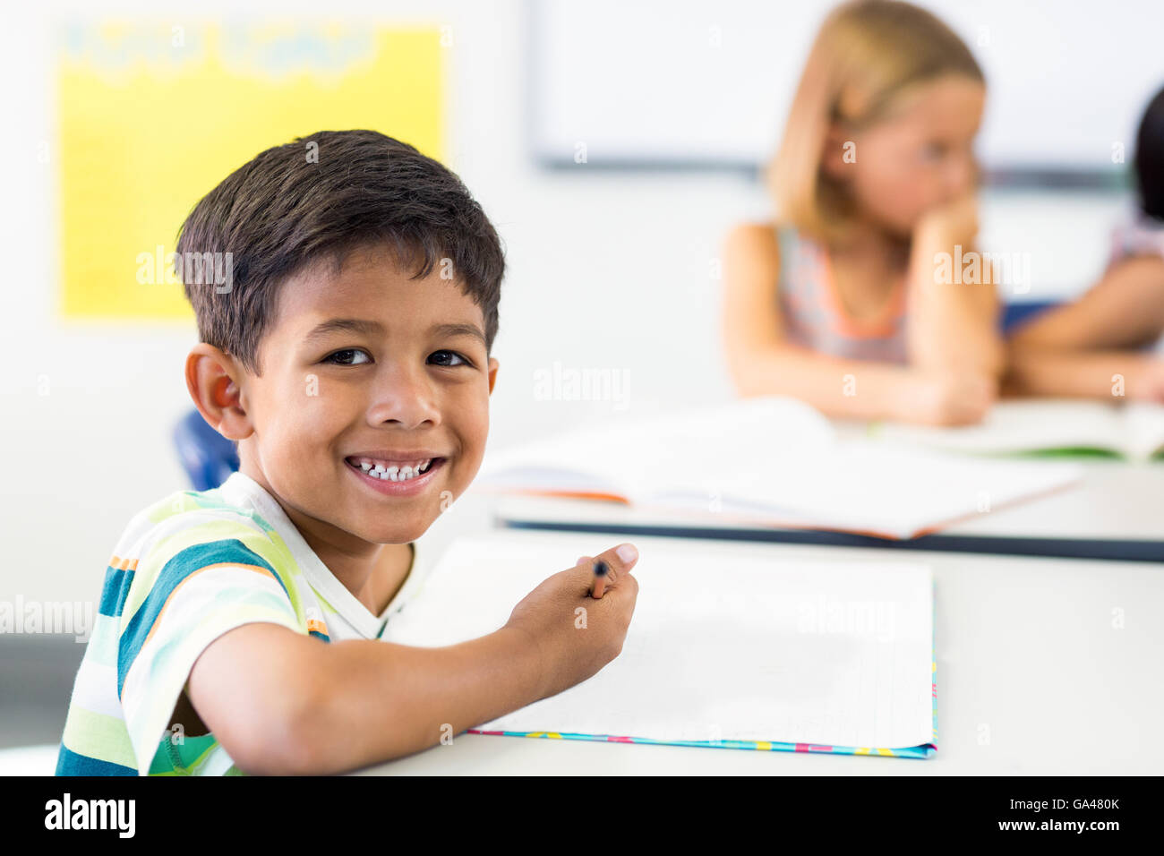 Boy writing on book against classmate Stock Photo - Alamy