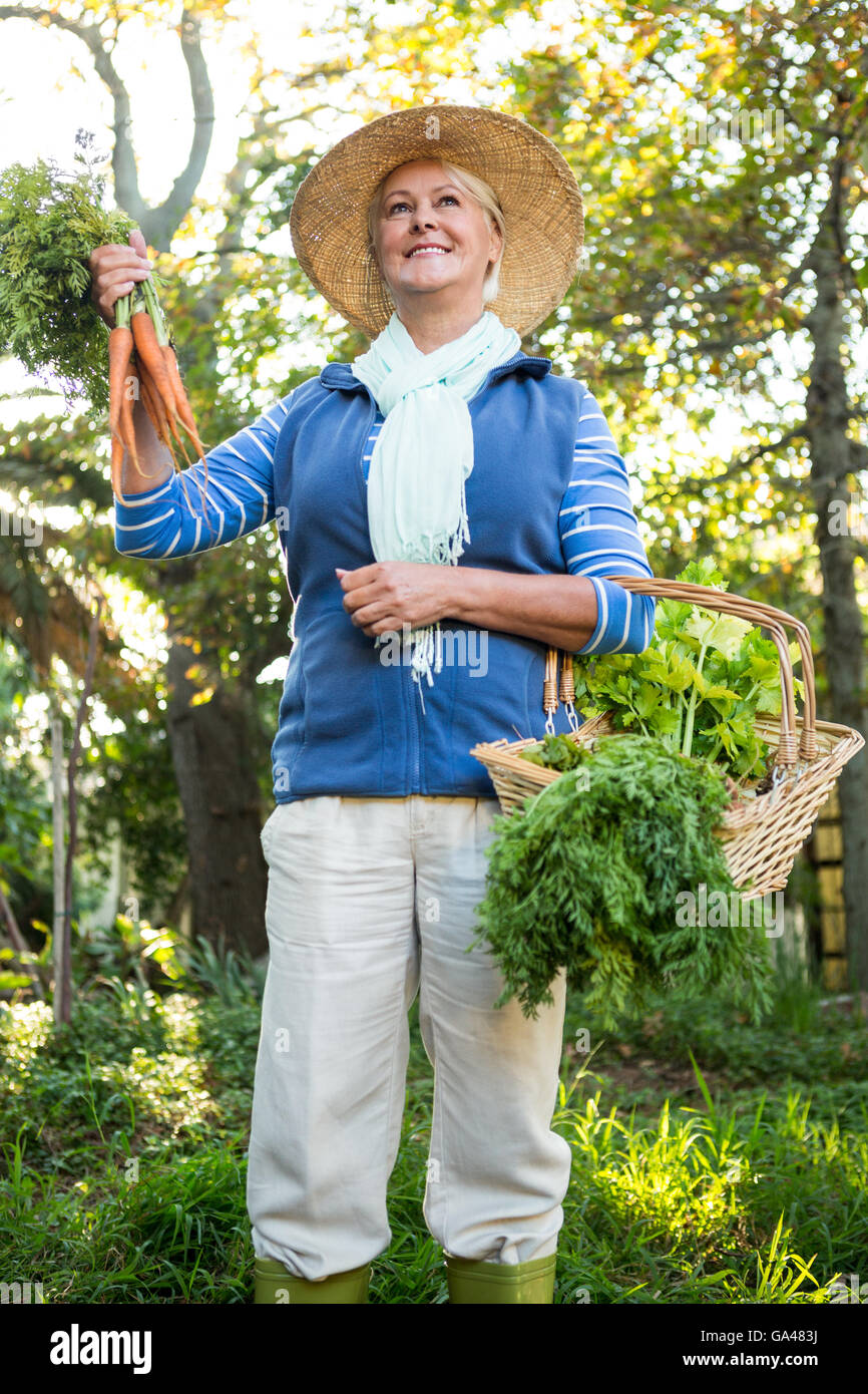 Happy gardener standing with fresh vegetables at garden Stock Photo - Alamy