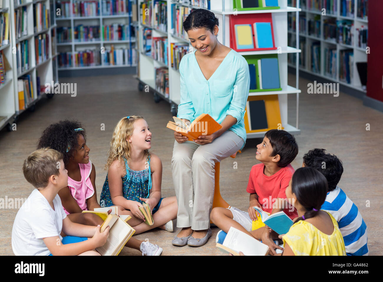 Teacher with students reading books Stock Photo - Alamy