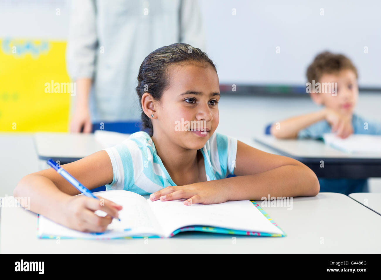 Smiling girl writing on book Stock Photo - Alamy