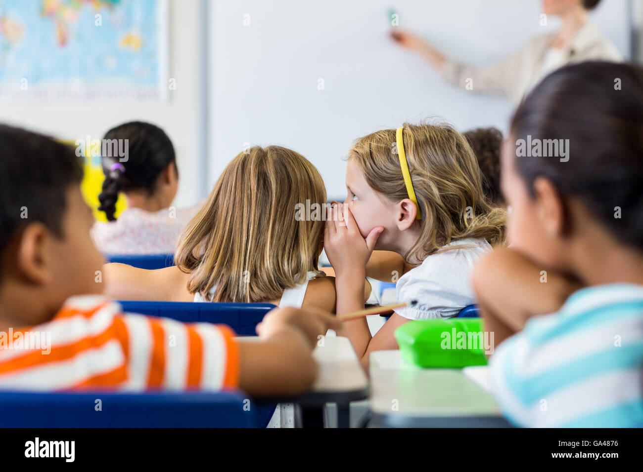 Schoolgirls gossiping in classroom Stock Photo - Alamy