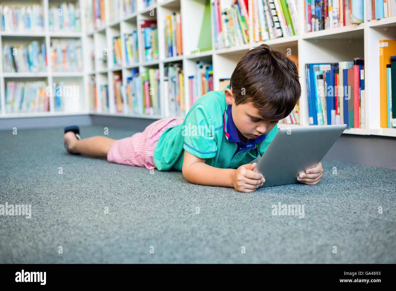 Boy using digital tablet in school library Stock Photo - Alamy